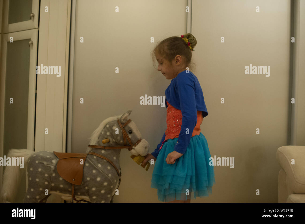 Little girl plays with a horse gurney. The child is sitting on a horse ...