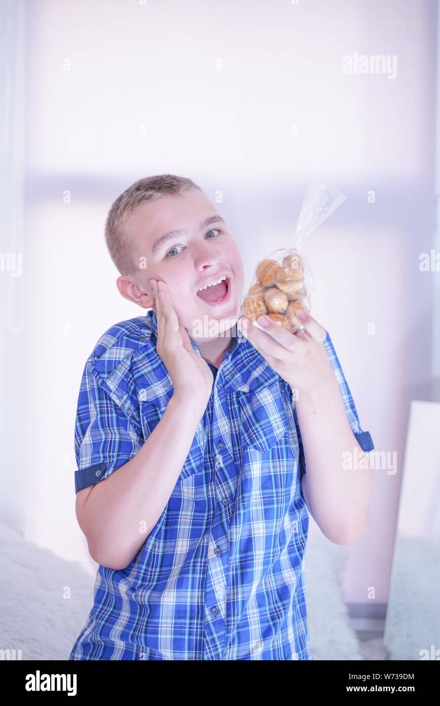 cute hungry teenager boy with fresh small bake sweets on white room ...
