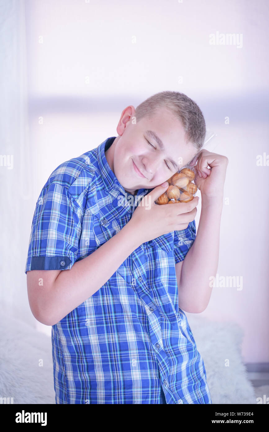 cute hungry teenager boy with fresh small bake sweets on white room ...