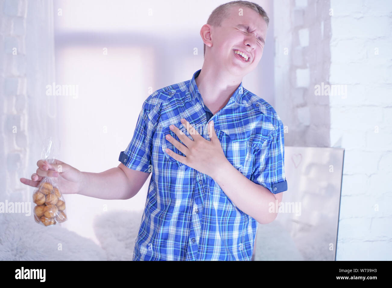 cute hungry teenager boy with fresh small bake sweets on white room ...