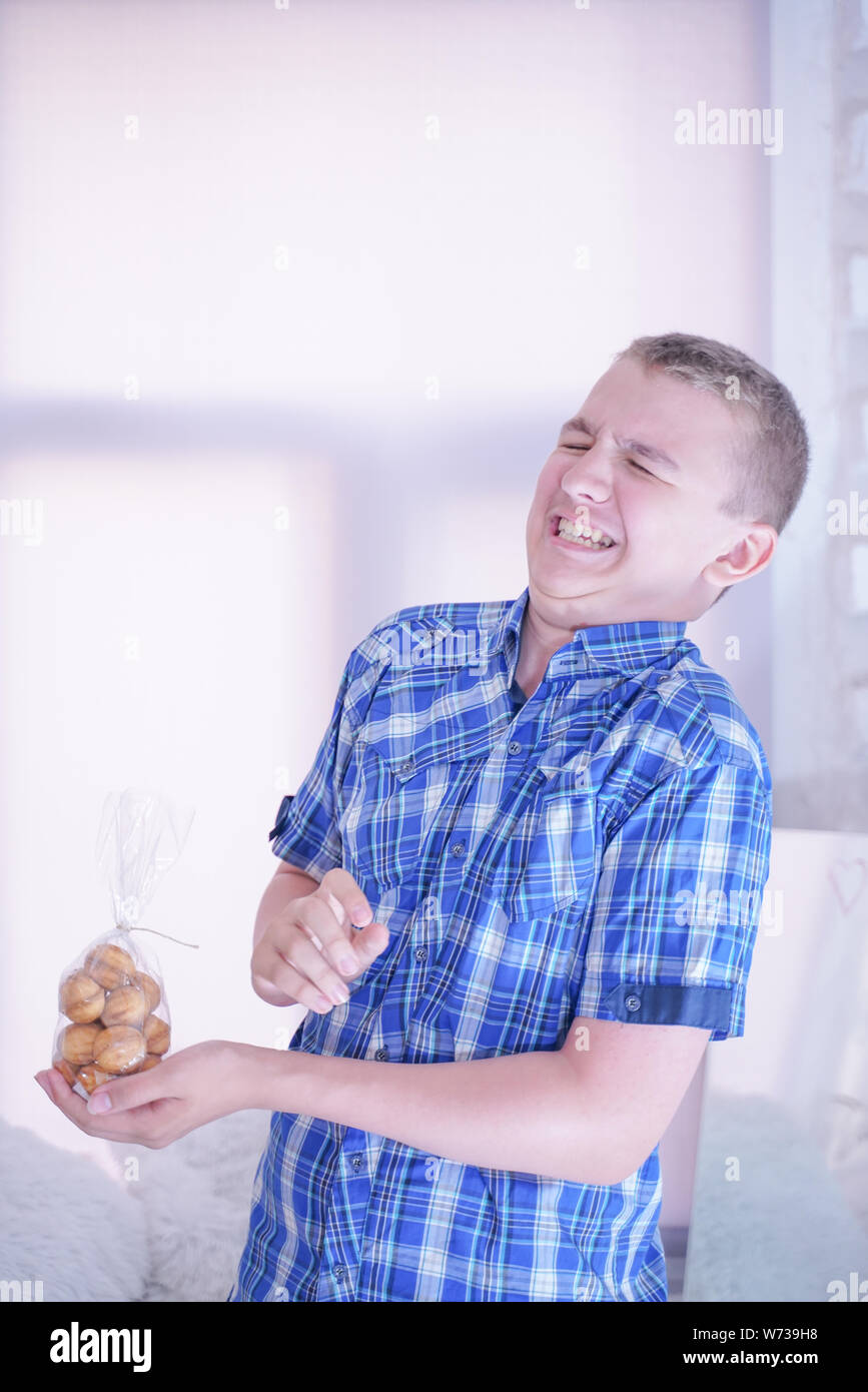 cute hungry teenager boy with fresh small bake sweets on white room ...