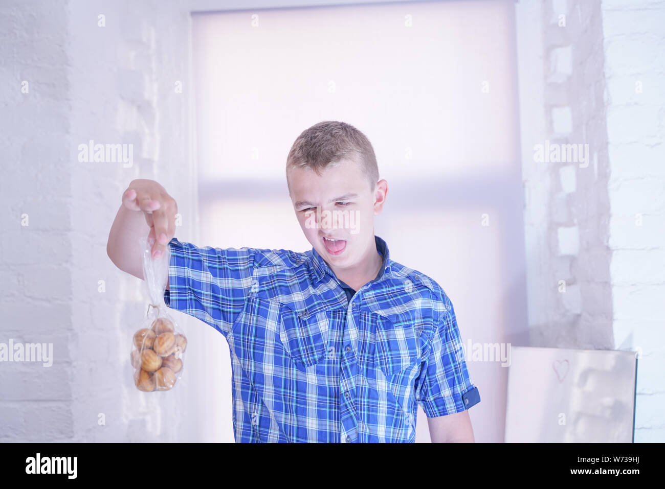 cute hungry teenager boy with fresh small bake sweets on white room ...