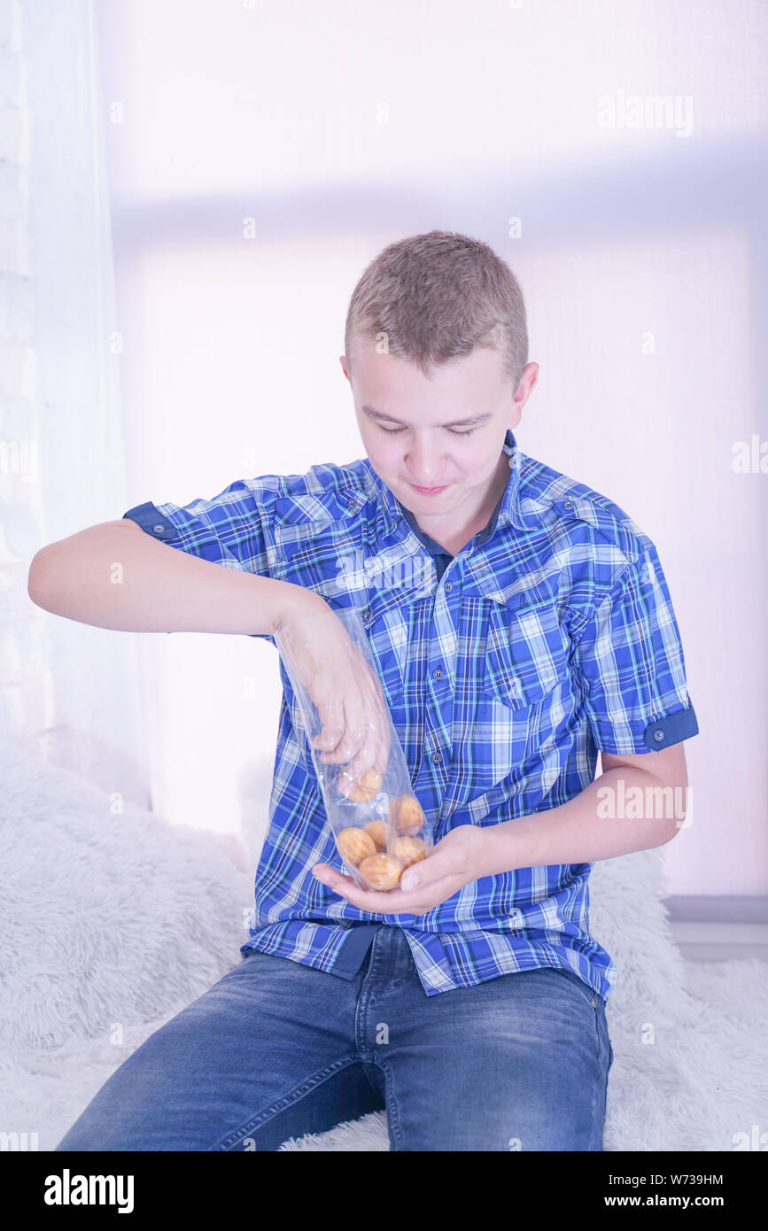 cute hungry teenager boy with fresh small bake sweets on white room ...