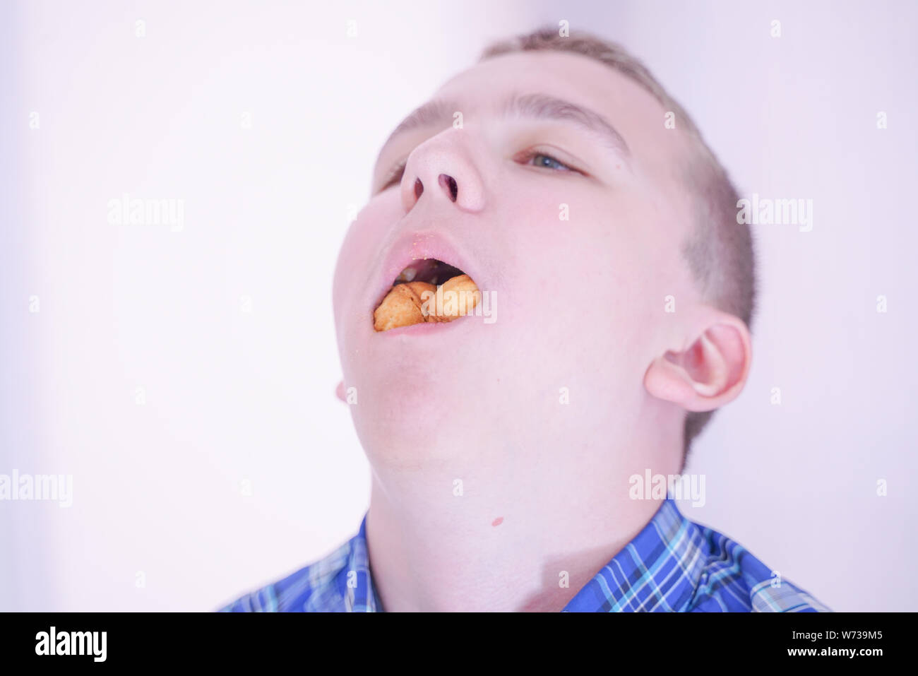cute hungry teenager boy with fresh small bake sweets on white room ...