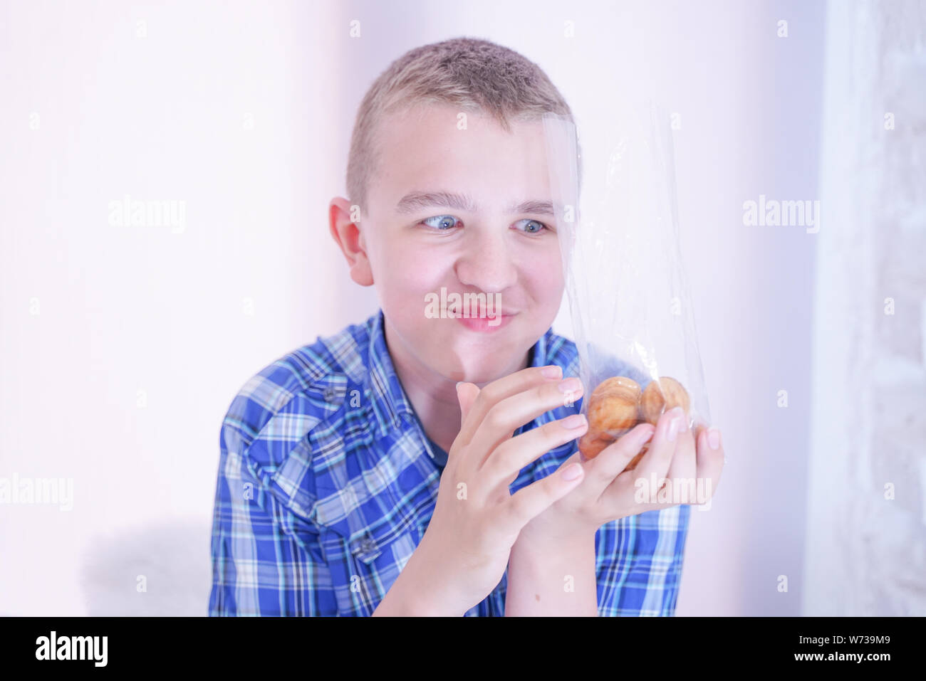 cute hungry teenager boy with fresh small bake sweets on white room ...