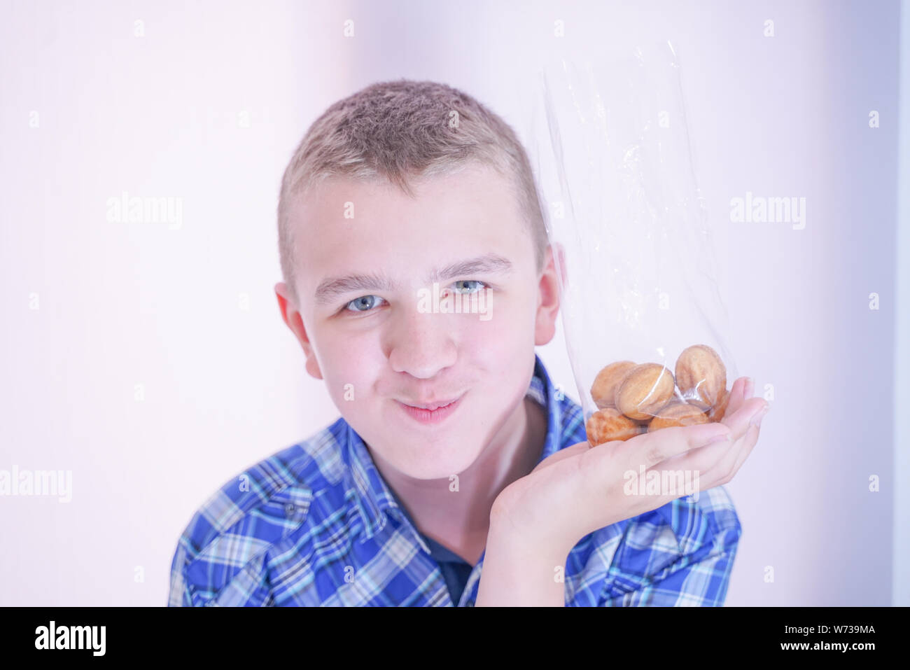 cute hungry teenager boy with fresh small bake sweets on white room ...