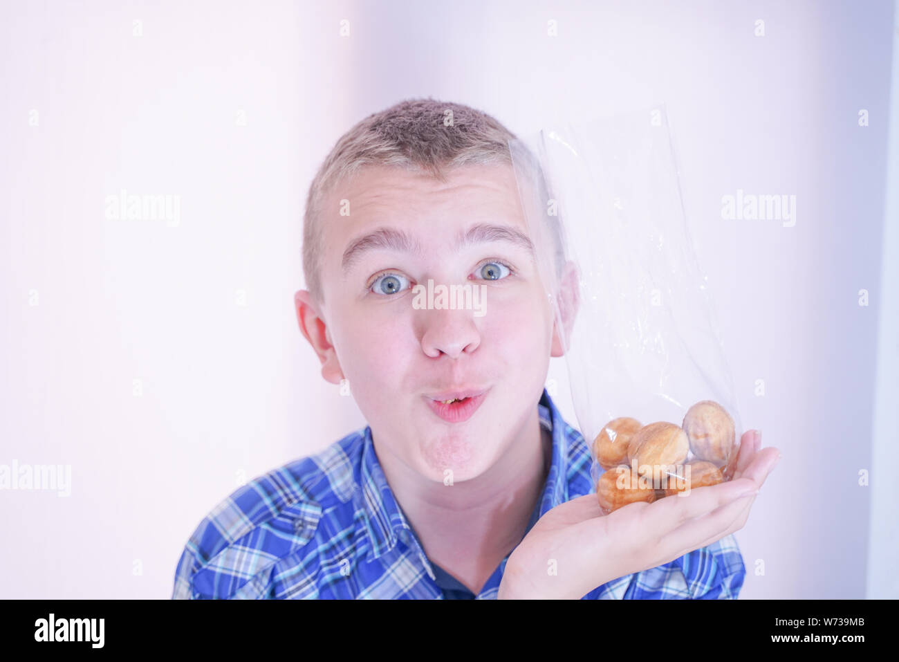 cute hungry teenager boy with fresh small bake sweets on white room ...