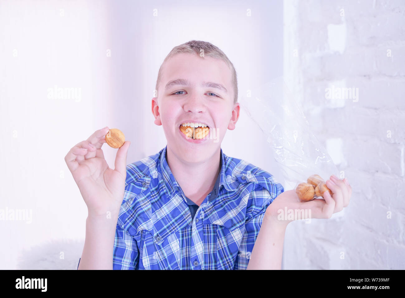 cute hungry teenager boy with fresh small bake sweets on white room ...