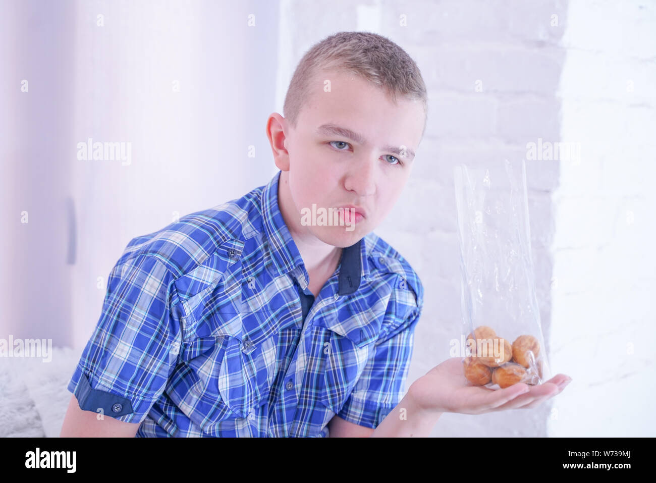 cute hungry teenager boy with fresh small bake sweets on white room ...