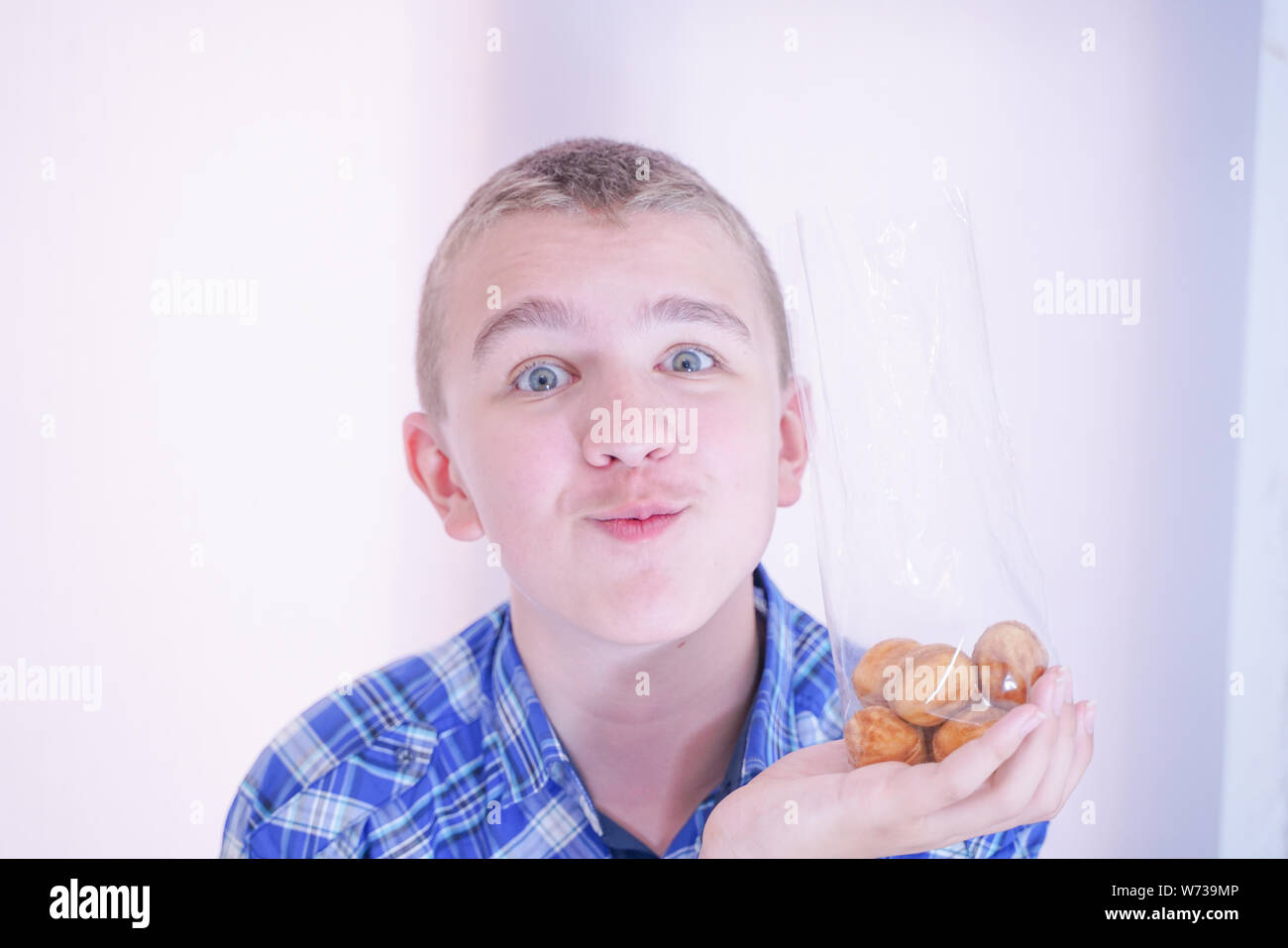 cute hungry teenager boy with fresh small bake sweets on white room ...