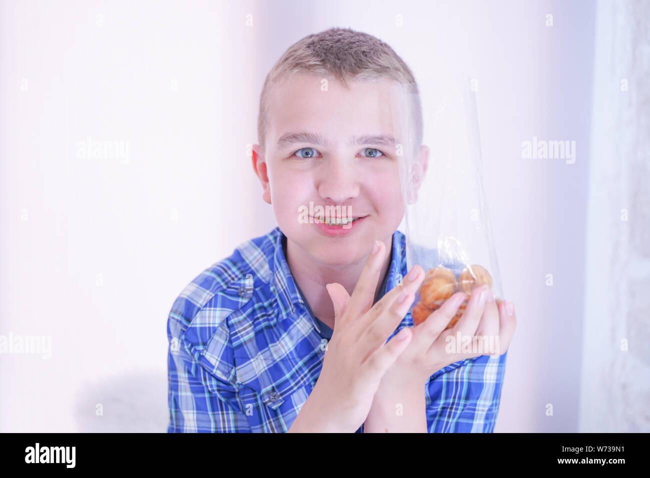 cute hungry teenager boy with fresh small bake sweets on white room ...