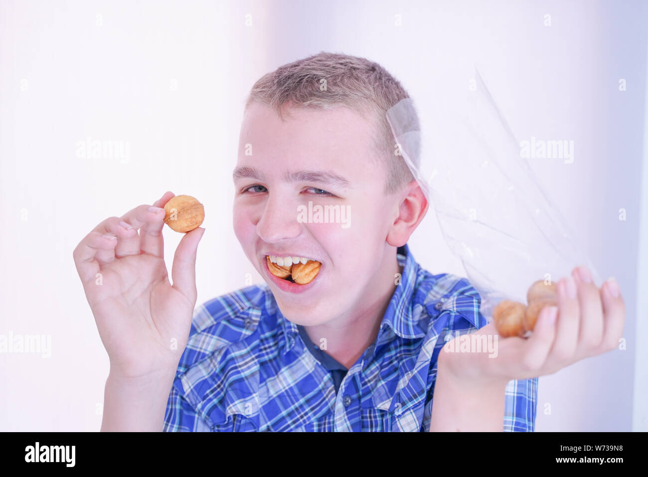 cute hungry teenager boy with fresh small bake sweets on white room ...