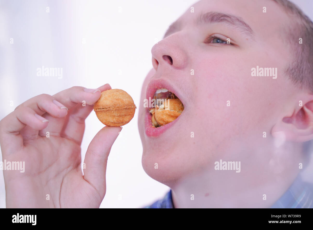 cute hungry teenager boy with fresh small bake sweets on white room ...