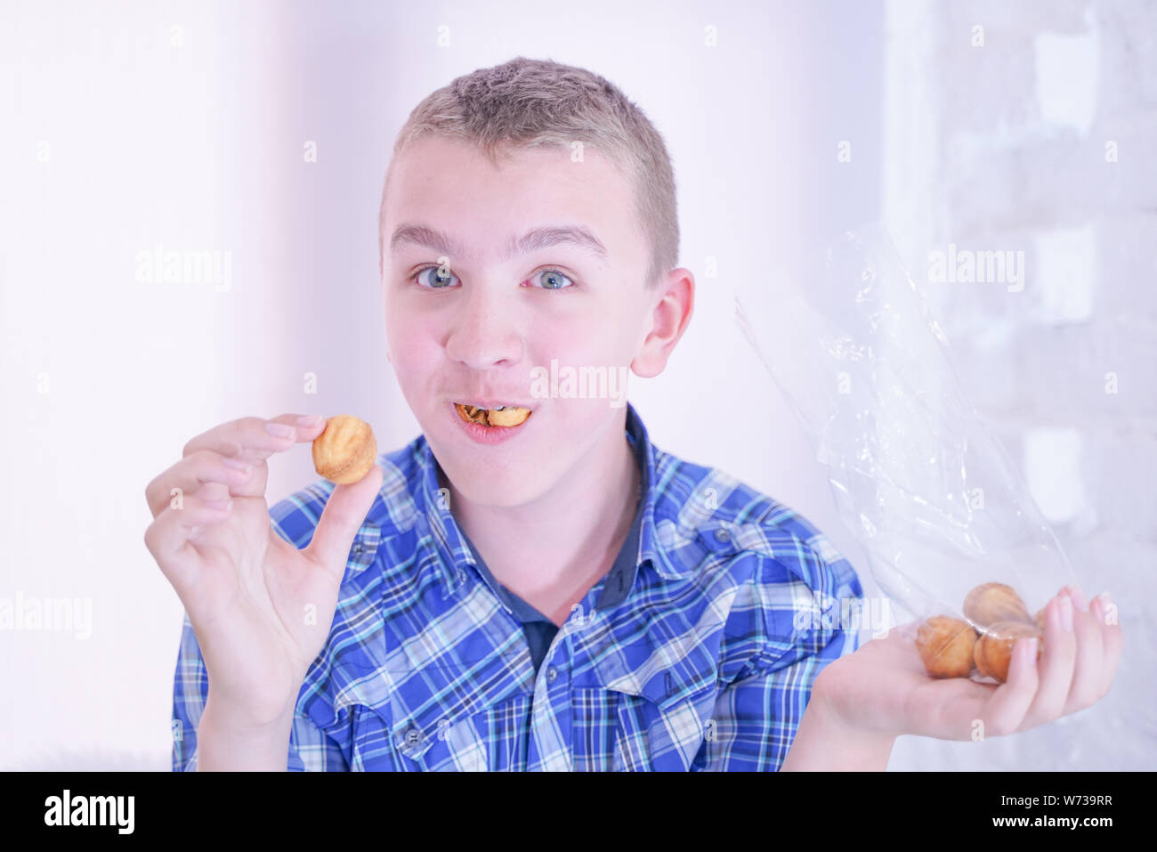 cute hungry teenager boy with fresh small bake sweets on white room ...