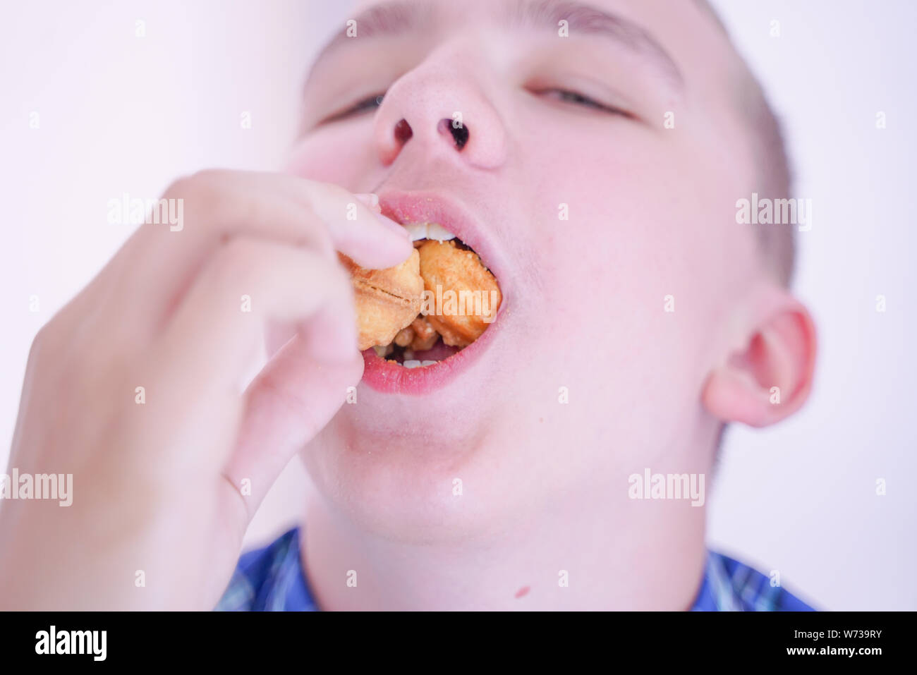 cute hungry teenager boy with fresh small bake sweets on white room ...