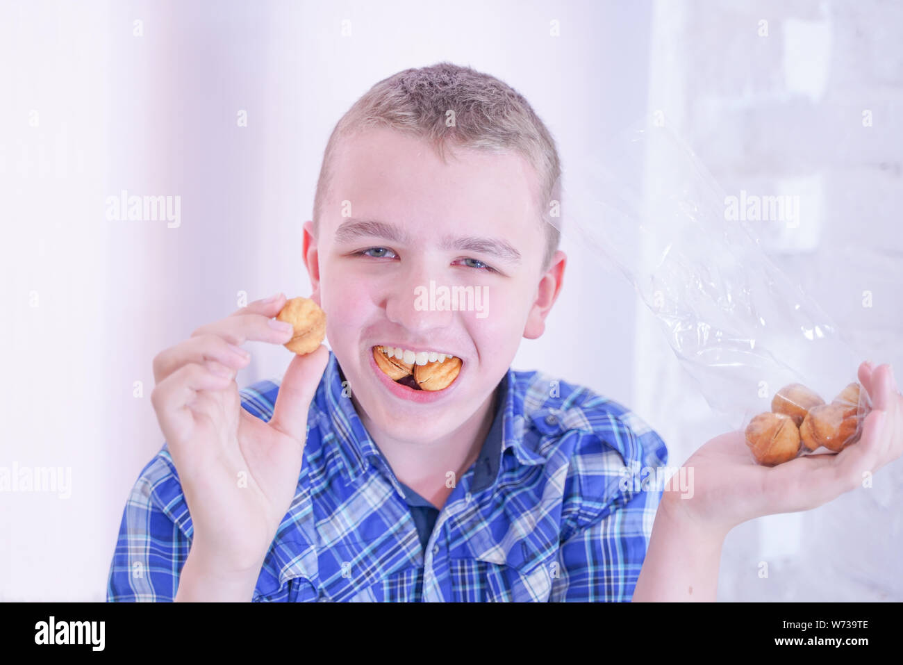 cute hungry teenager boy with fresh small bake sweets on white room ...