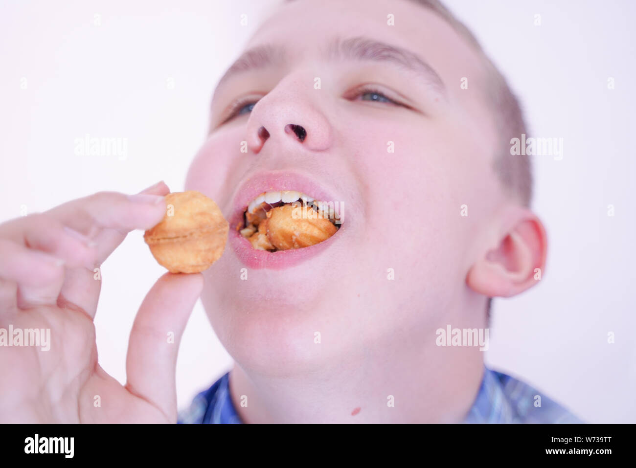cute hungry teenager boy with fresh small bake sweets on white room ...