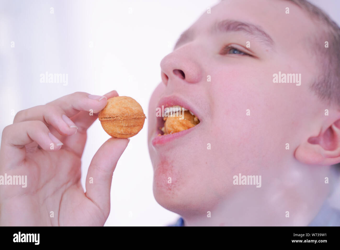 cute hungry teenager boy with fresh small bake sweets on white room ...