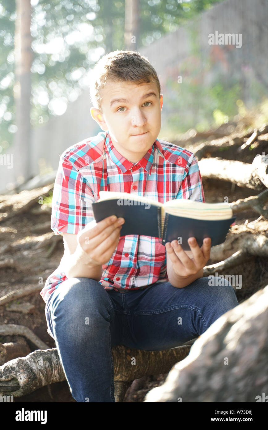 Teenage boy reading exercise book on the nature Stock Photo - Alamy