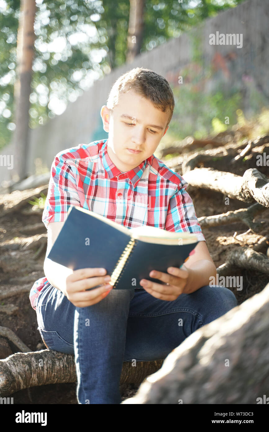 Teenage boy reading exercise book on the nature Stock Photo - Alamy