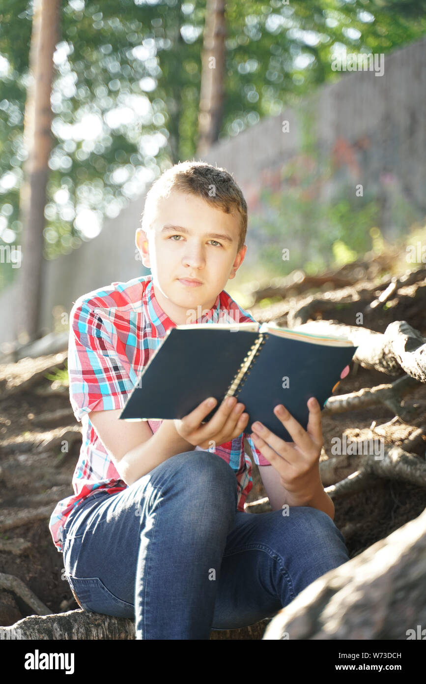 Teenage boy reading exercise book on the nature Stock Photo - Alamy