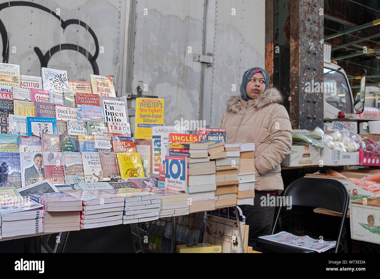 A Hispanic American woman selling Spanish language books outdoors under ...