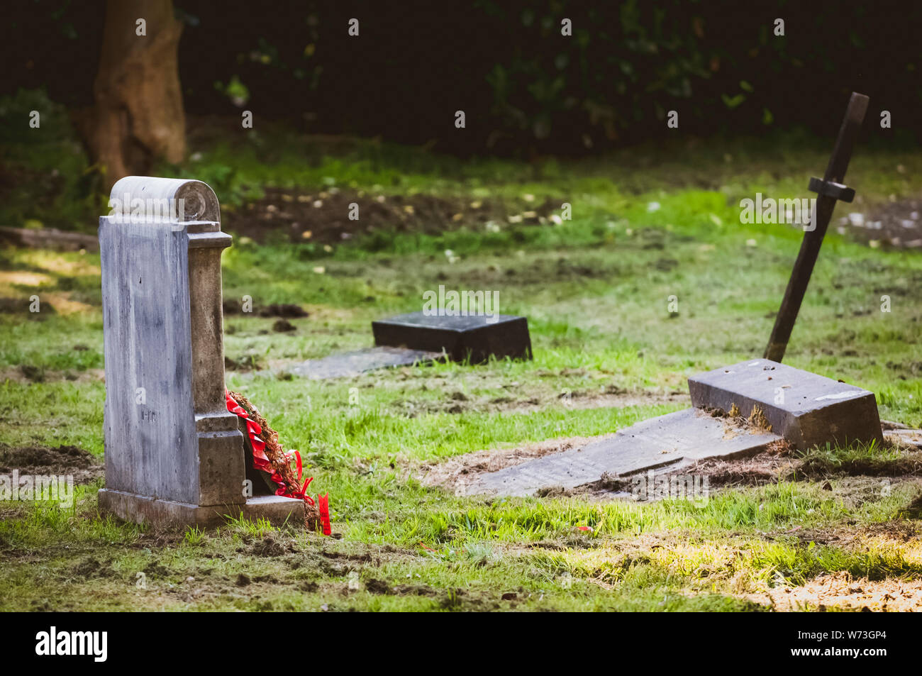 Image of a broken gravestone with a single cross behind it and a ...