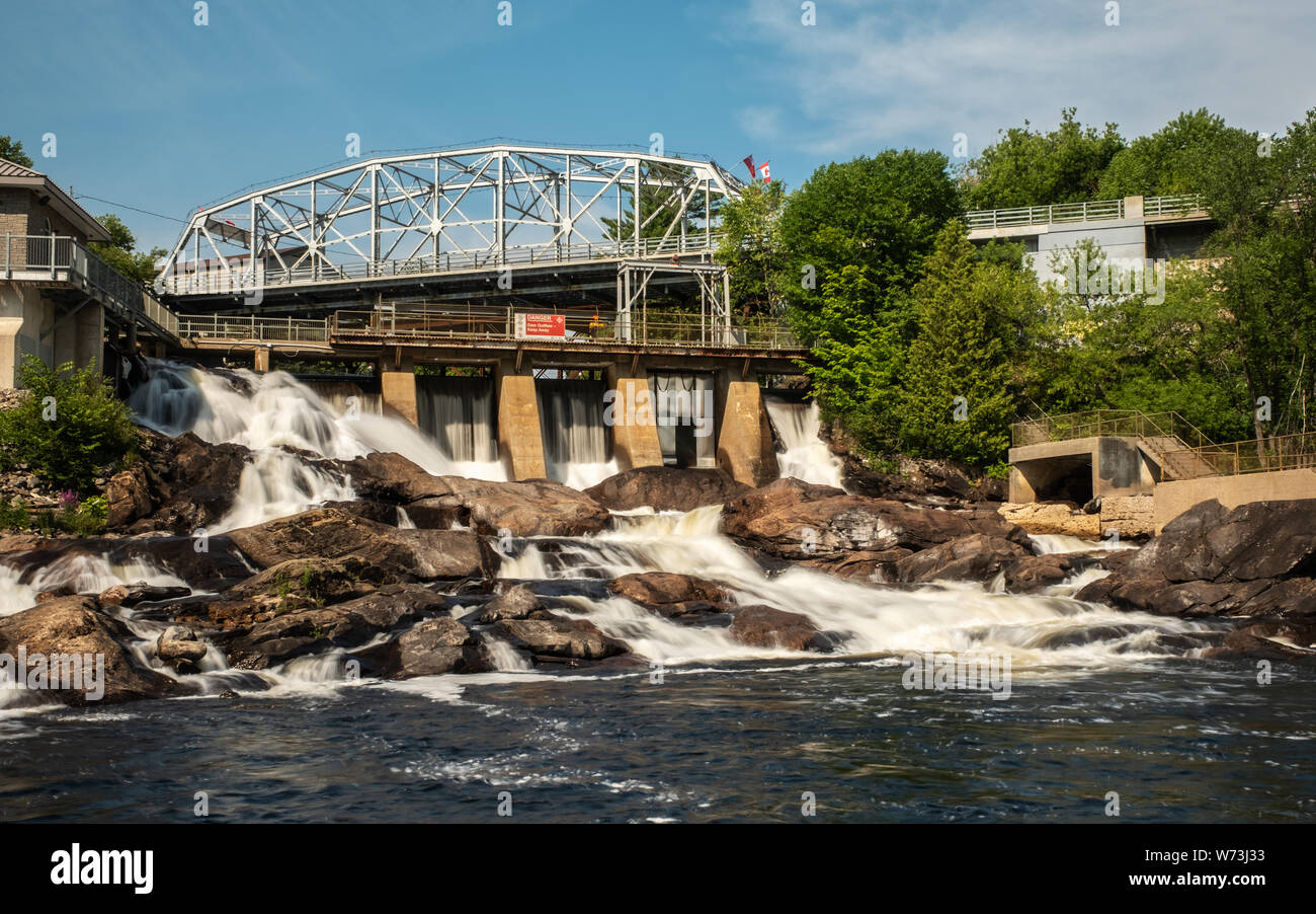 Water rushes through a dam and down onto the rocks below in downtown ...