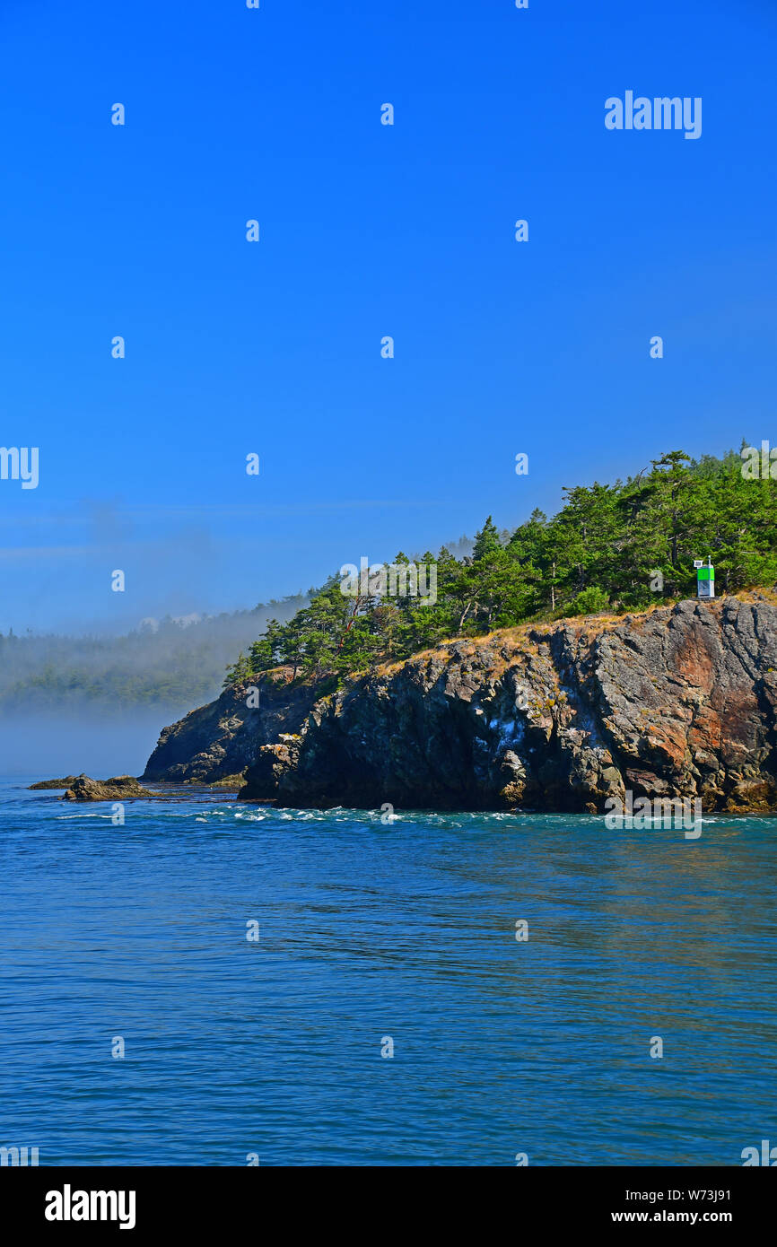 Morning fog hugs the coastline of Deception Pass near the San Juan ...