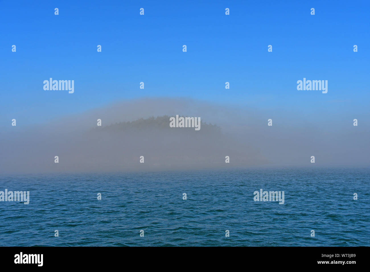 Morning fog hugs the coastline of Deception Pass near the San Juan ...