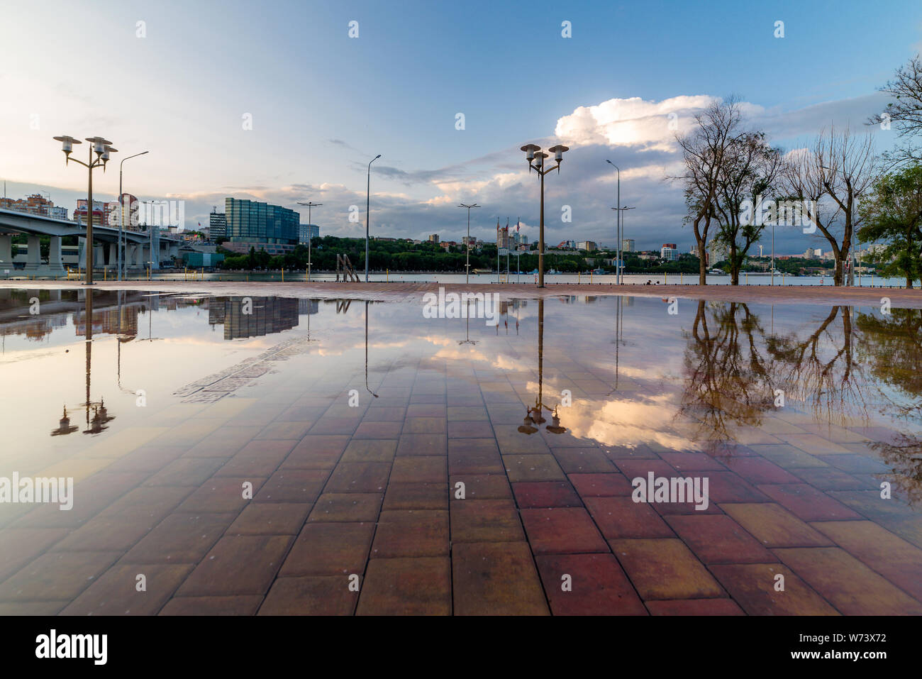 Reflection of bridge and sky into puddle on riverwalk Stock Photo - Alamy
