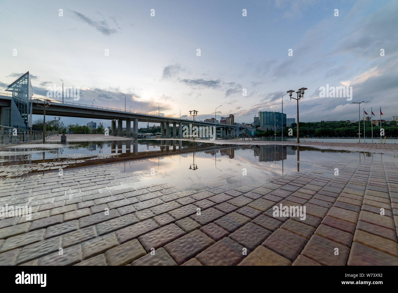 Reflection of bridge and sky into puddle on riverwalk Stock Photo - Alamy