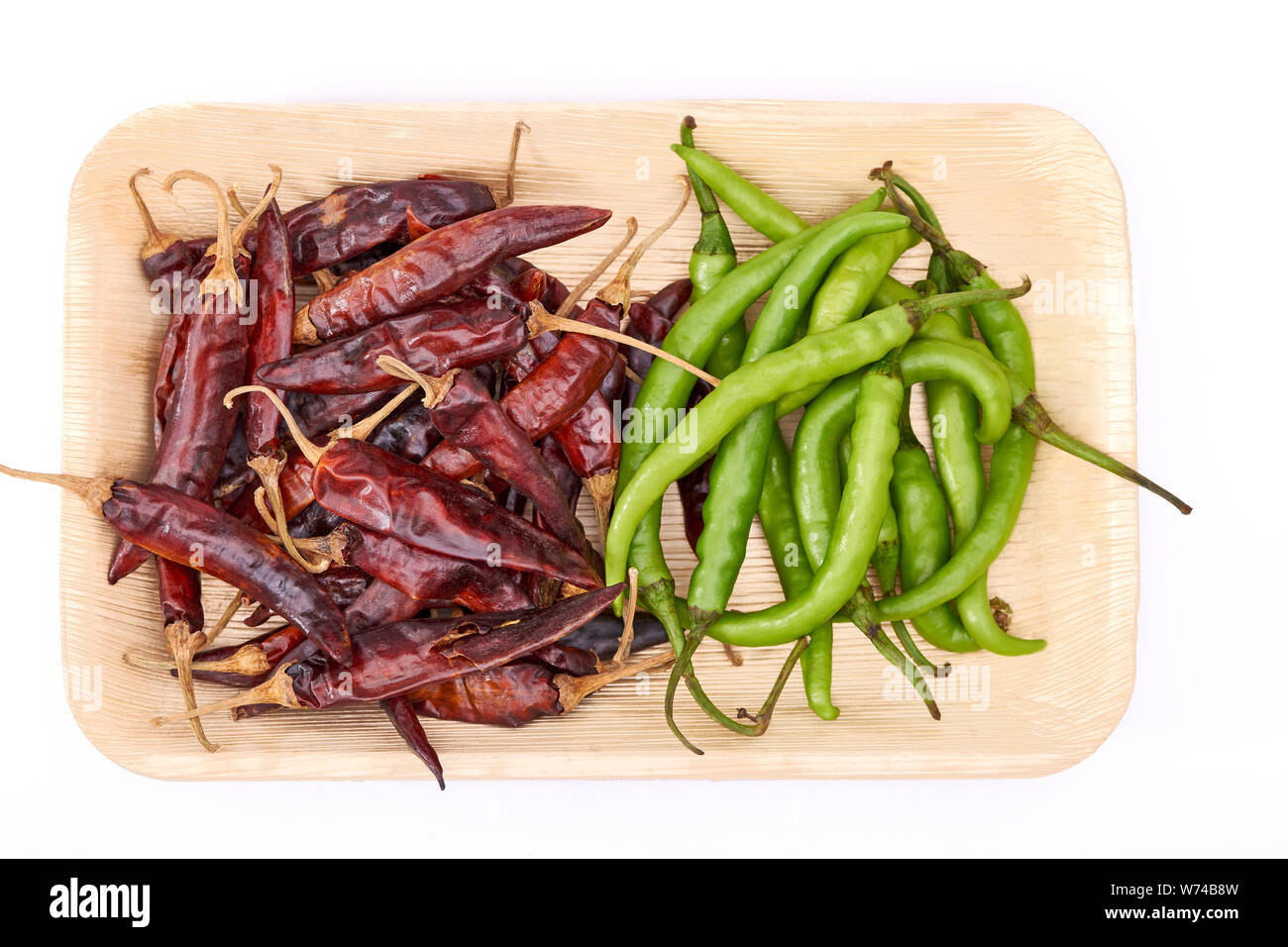 Tray with dried red chillies and fresh green chillies on a white ...
