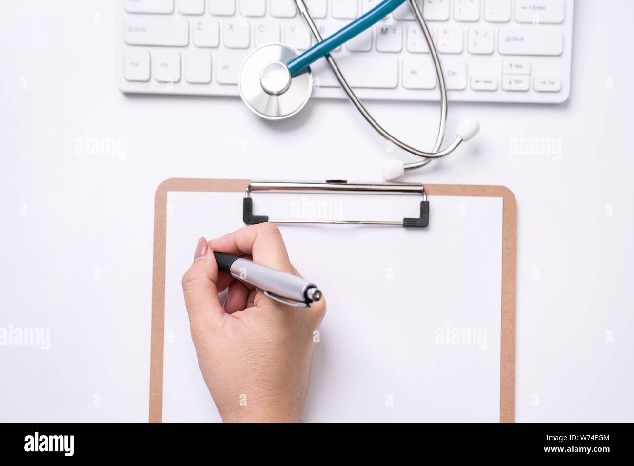 Female doctor writing a medical record case over clipboard on white ...
