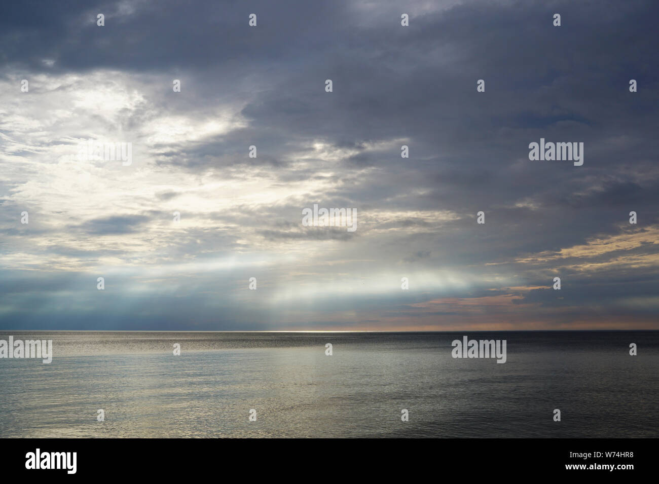 Sunset over the sea, where the sun's rays shine above the surface of ...