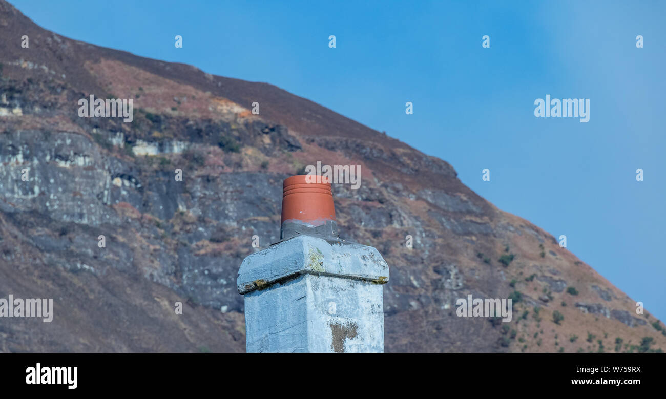 An old chimney isolated against a mountain and crisp blue sky ...