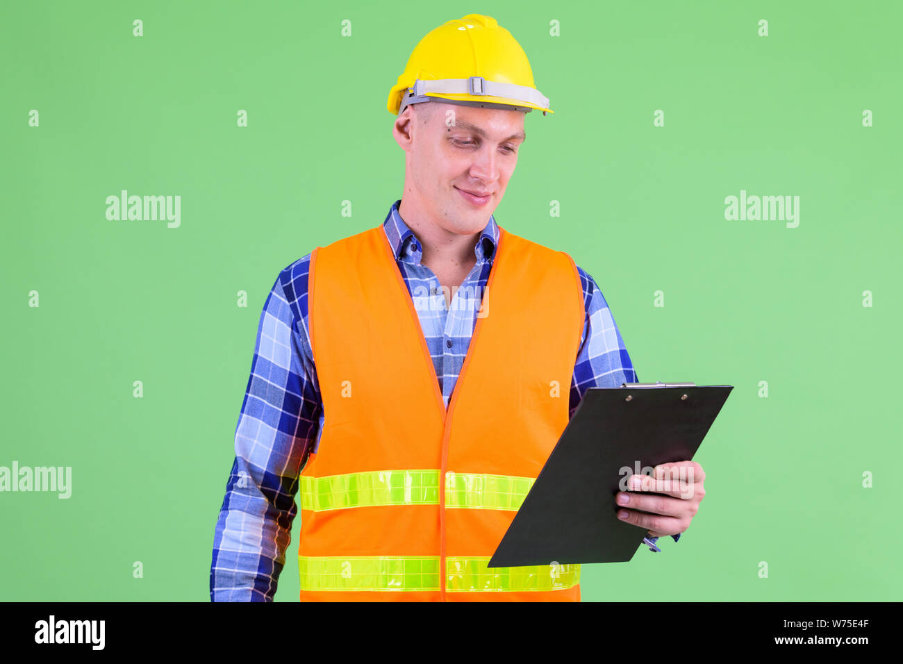 Young man construction worker reading on clipboard Stock Photo - Alamy
