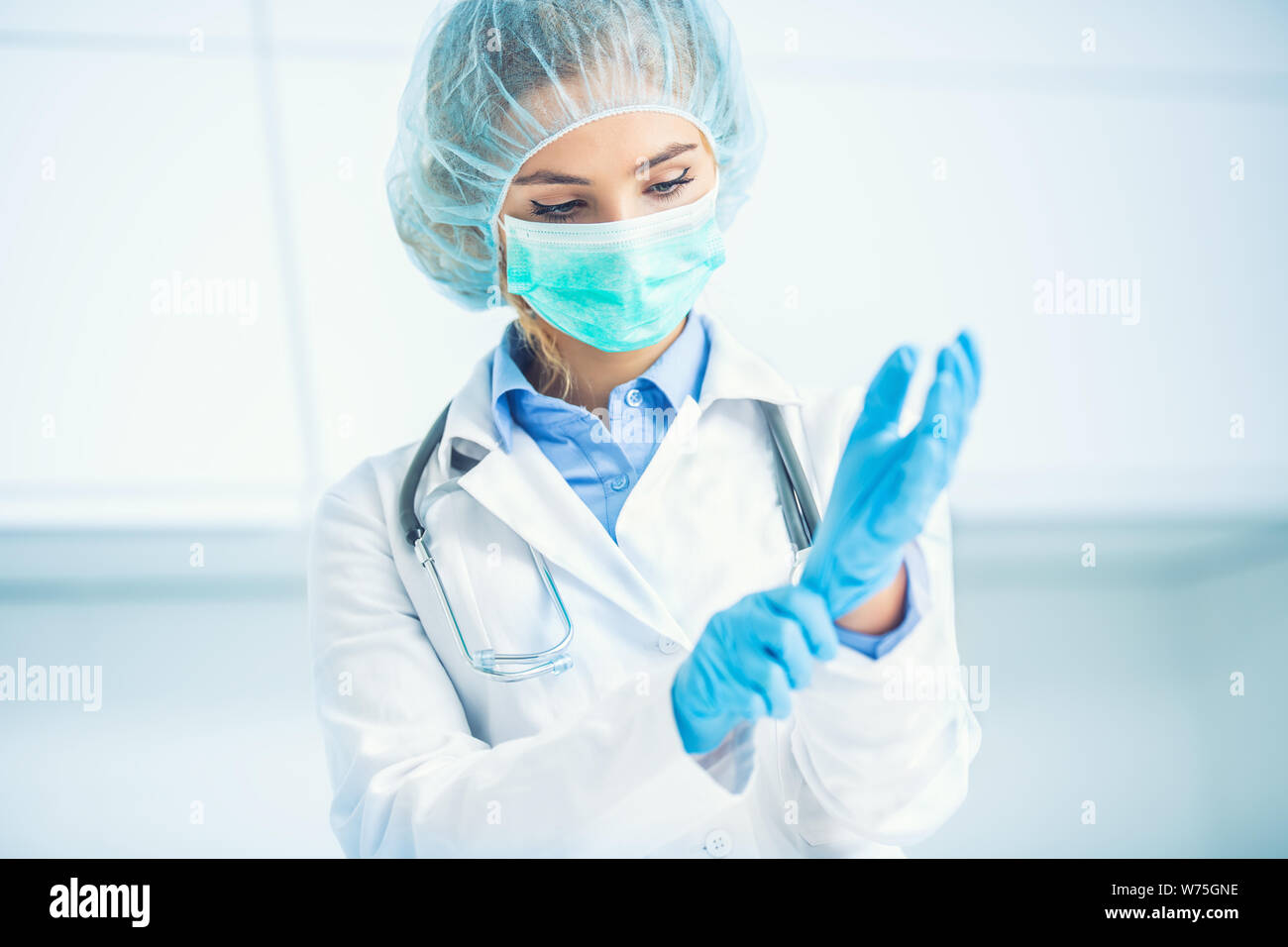 Doctor woman surgeon specialist in sterile clothing putting on surgical ...