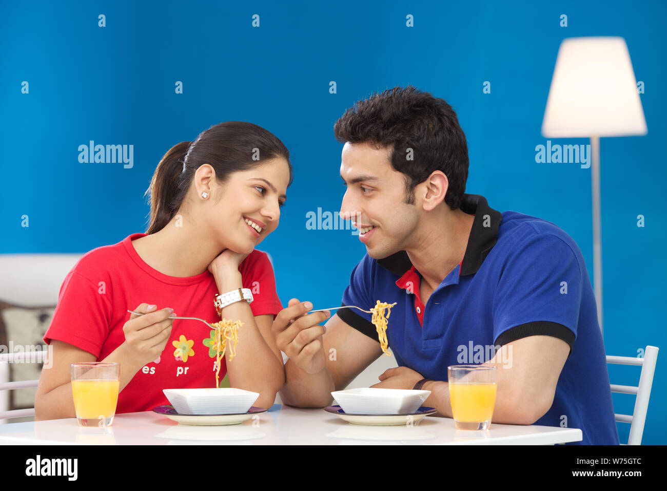 Young couple eating noodles at breakfast table Stock Photo - Alamy