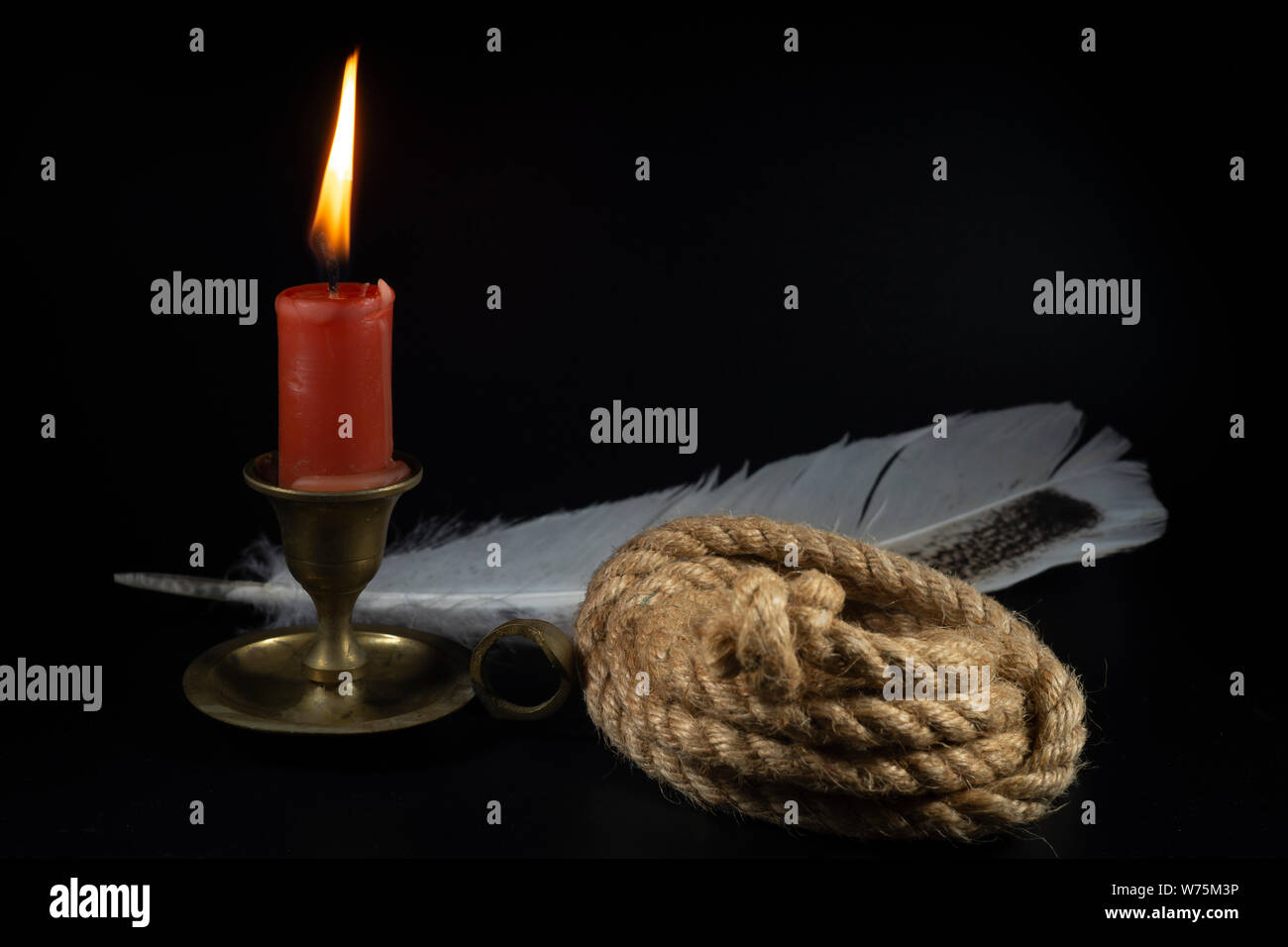 Coiled rope with burning candle in a vintage brass candlestick and ...