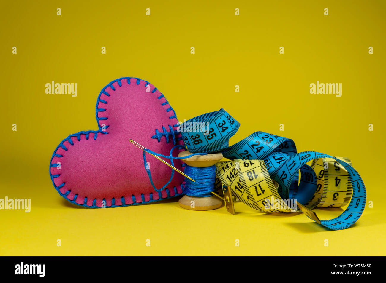 Hand stitched fabric heart, tape measure and spool of thread with ...