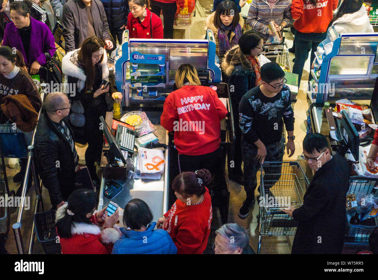 Chinese customers queue up to pay their purchases at a supermarket ...