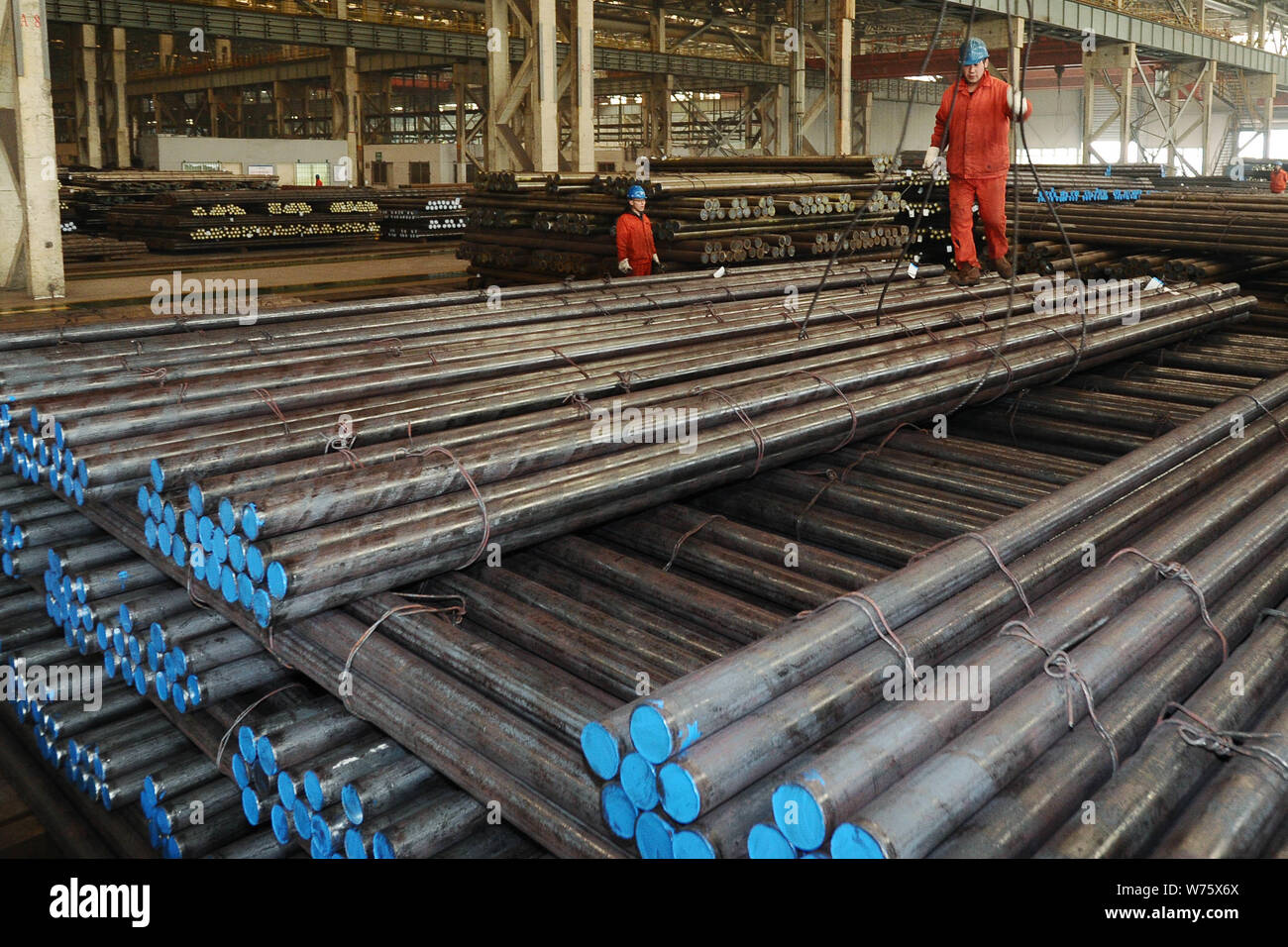 --FILE--A Chinese worker directs a crane to lift reinforcing steel rods ...