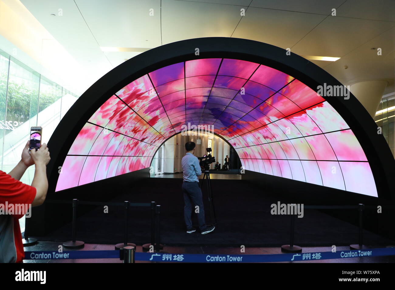 Visitors take photos of the world's largest OLED tunnel at Canton Tower ...