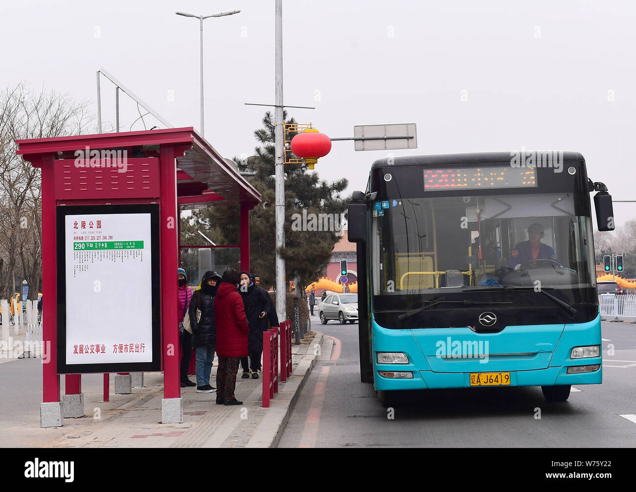 Citizens prepare to board a bus at a solar-powered bus stop in Shenyang ...