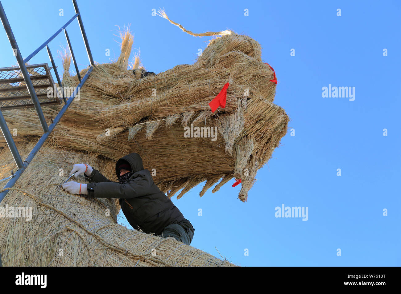 A Chinese worker builds two dragons made of straw, which are said to be ...