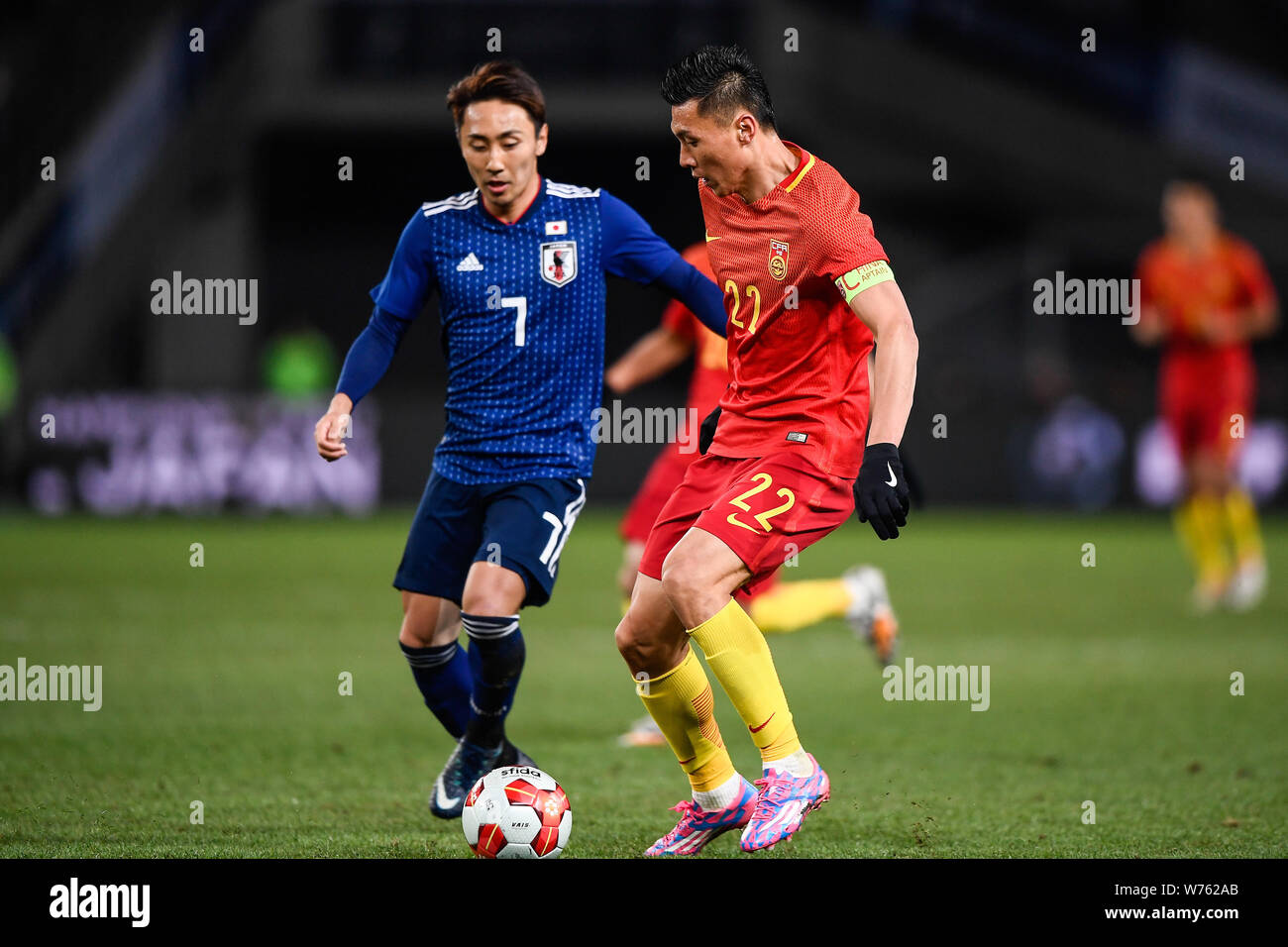 Kurata Shu, left, of Japan kicks the ball to make pass against Yu Dabao of China during the EAFF ...