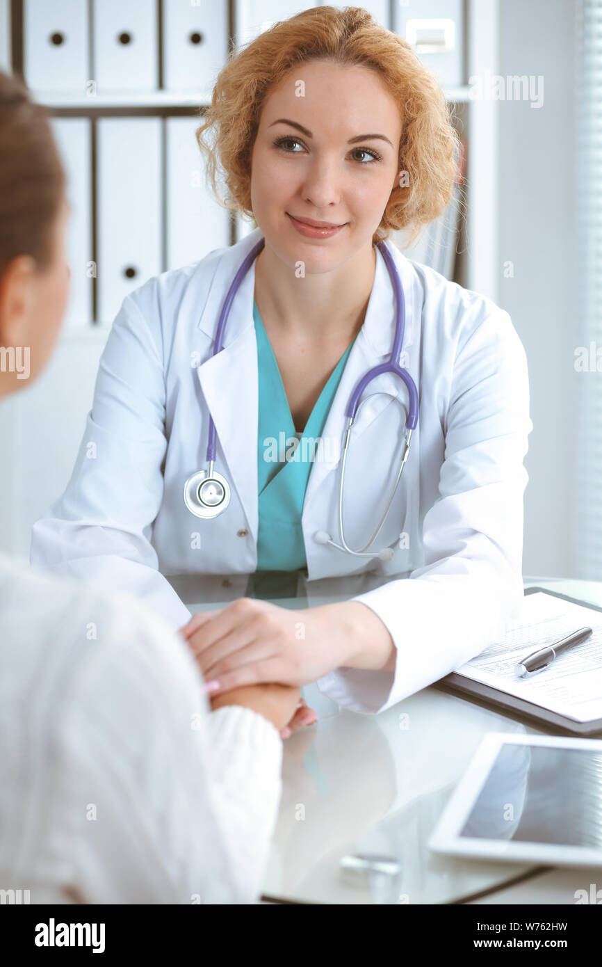 Doctor woman looking at patient while speaking to her and reassuring ...