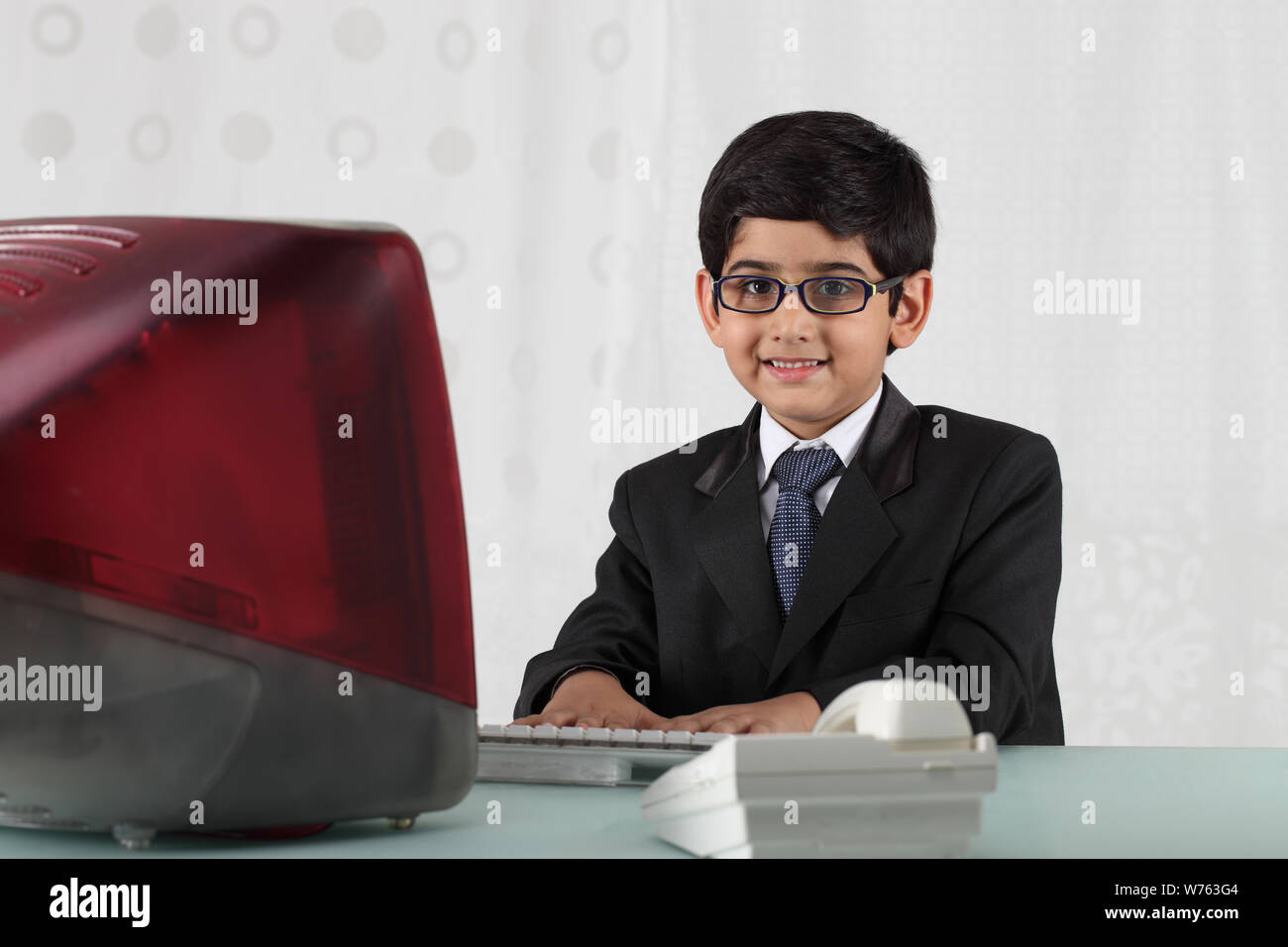 Indian boy pretending to be a businessman working on desktop pc Stock ...