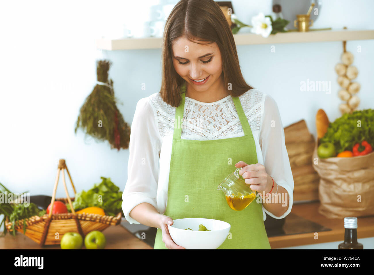 Young happy woman cooking in the kitchen. Healthy meal, lifestyle and ...